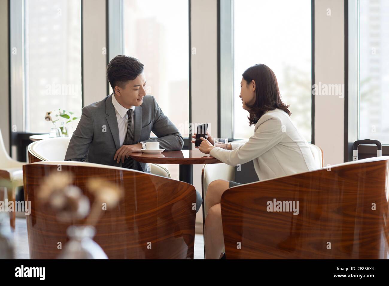 Confident business people talking in airport lounge Stock Photo - Alamy