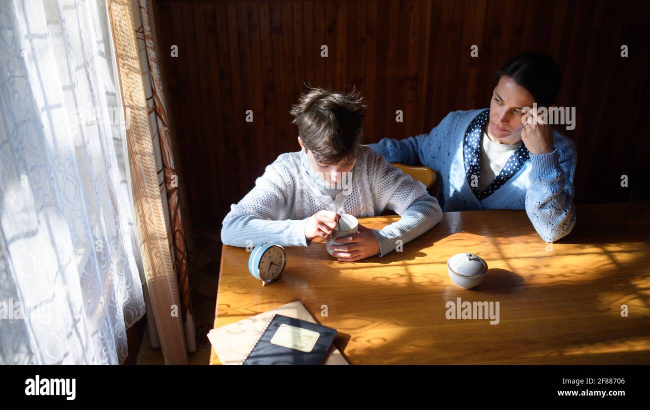 Portrait of sad poor mature mother with small daughter indoors at home ...