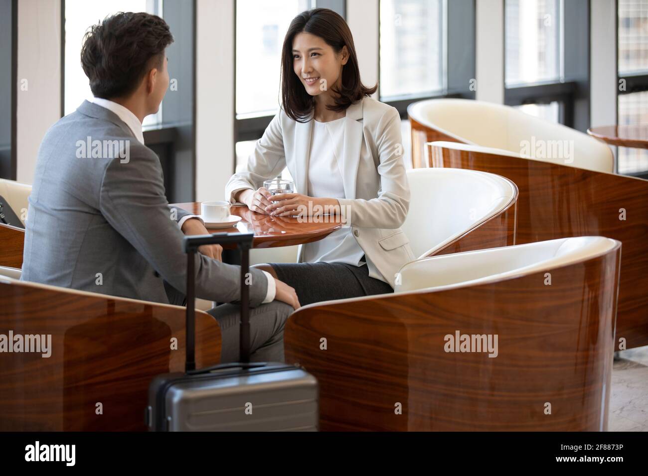 Confident business people talking in airport lounge Stock Photo - Alamy