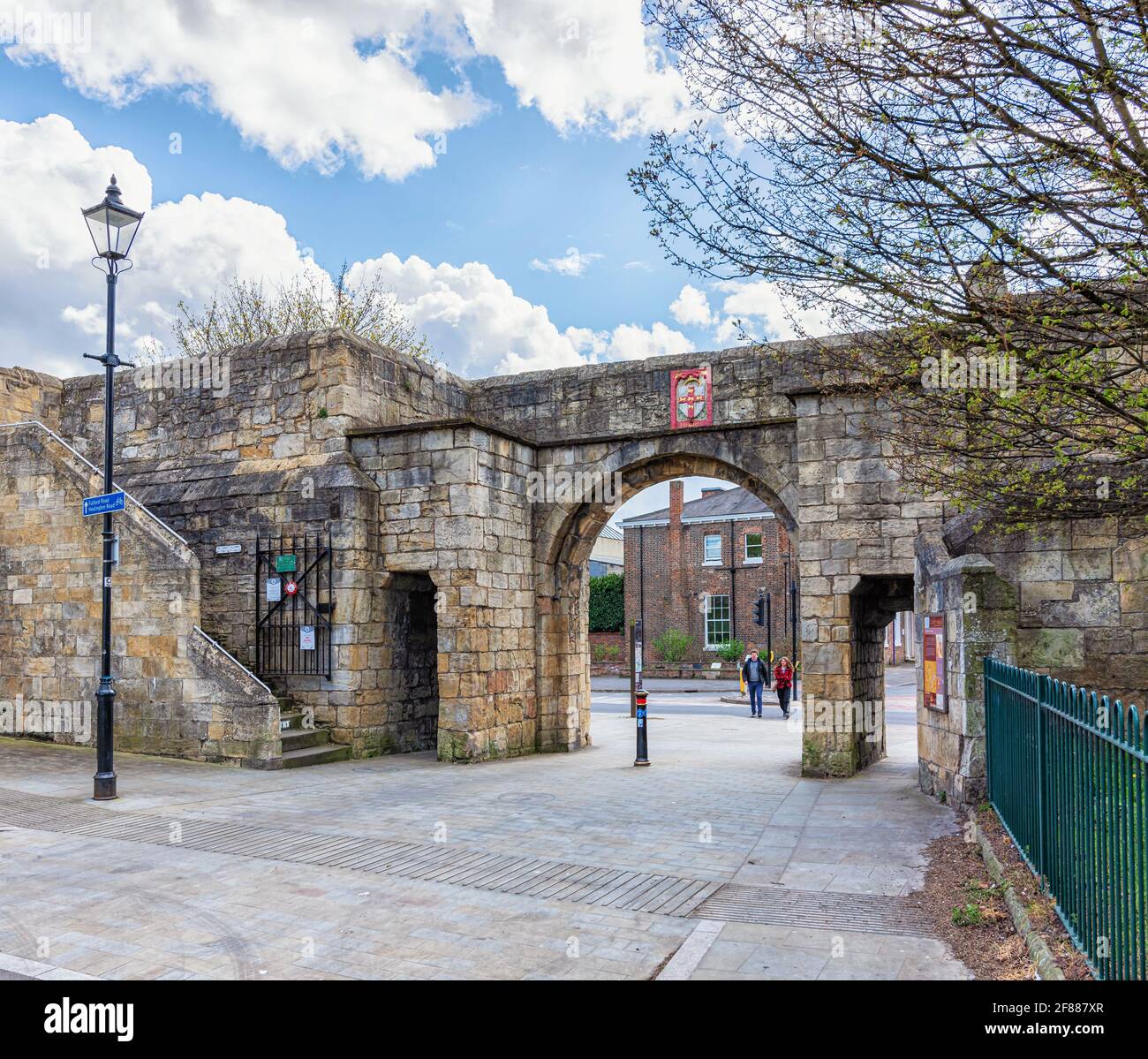 Ancient medieval gateway in a city wall. A lamppost and steps are to ...