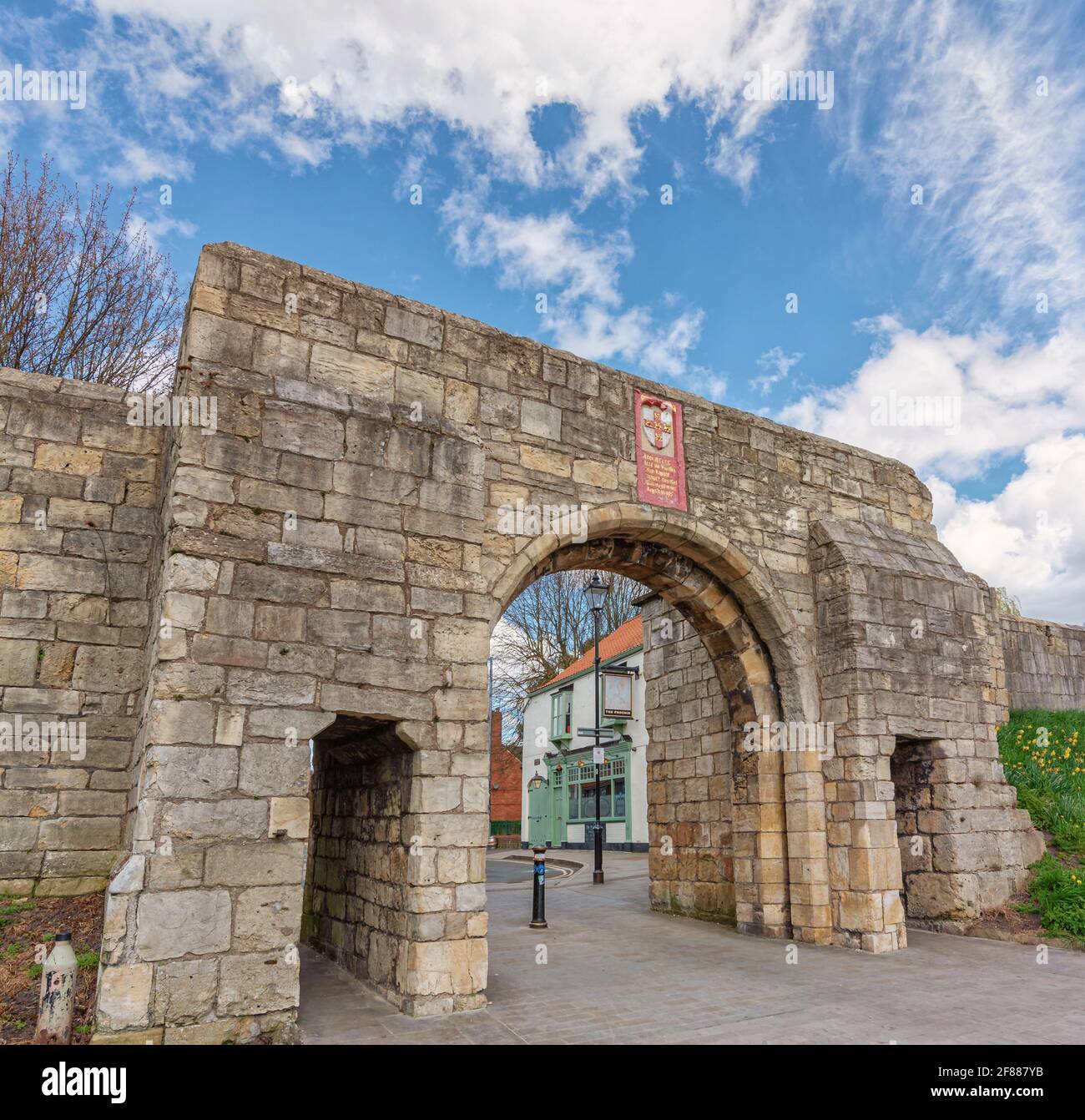 Ancient medieval gateway in a city wall. A public house can be seen ...