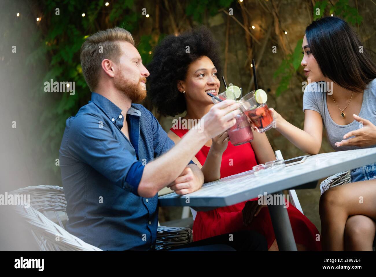 Friends having a great time in cafe, smiling and drinking cocktails ...