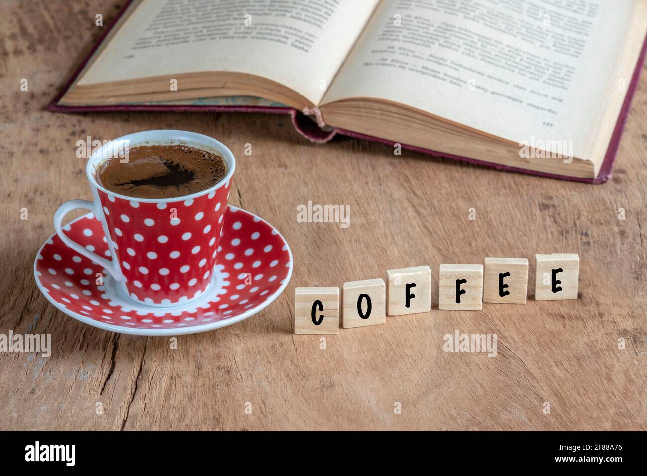 Book and coffee cup on wooden table with cube letters written coffee ...