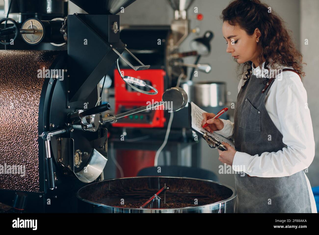 Coffee roaster machine and barista woman with tablet write pen at ...