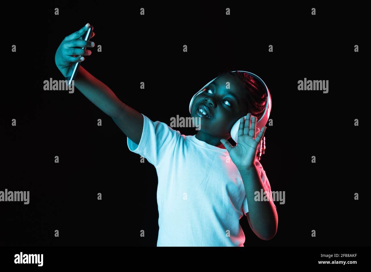 Portrait of little African-American girl isolated on dark background in ...