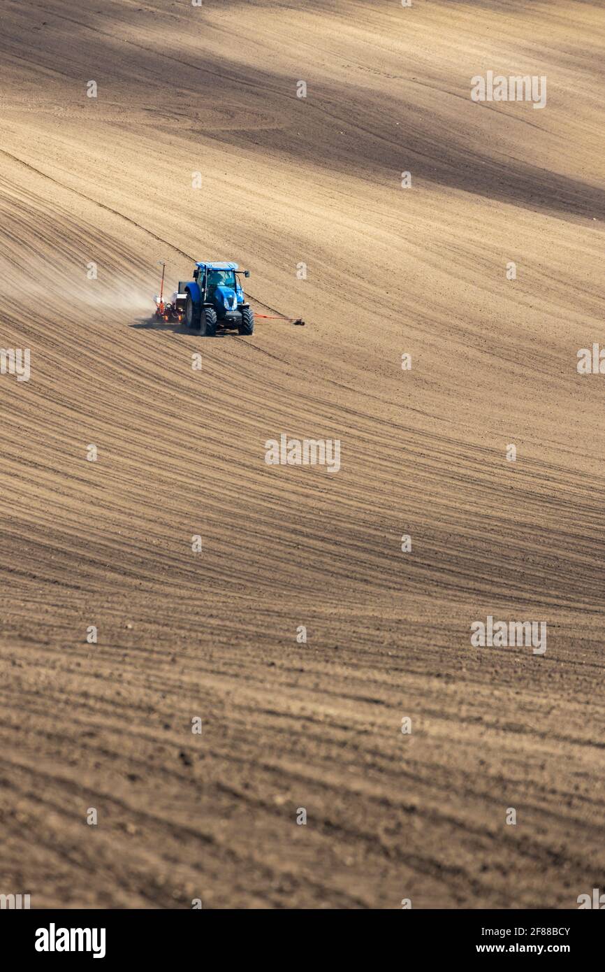 Tractor with seed drill in early spring landscape Stock Photo - Alamy