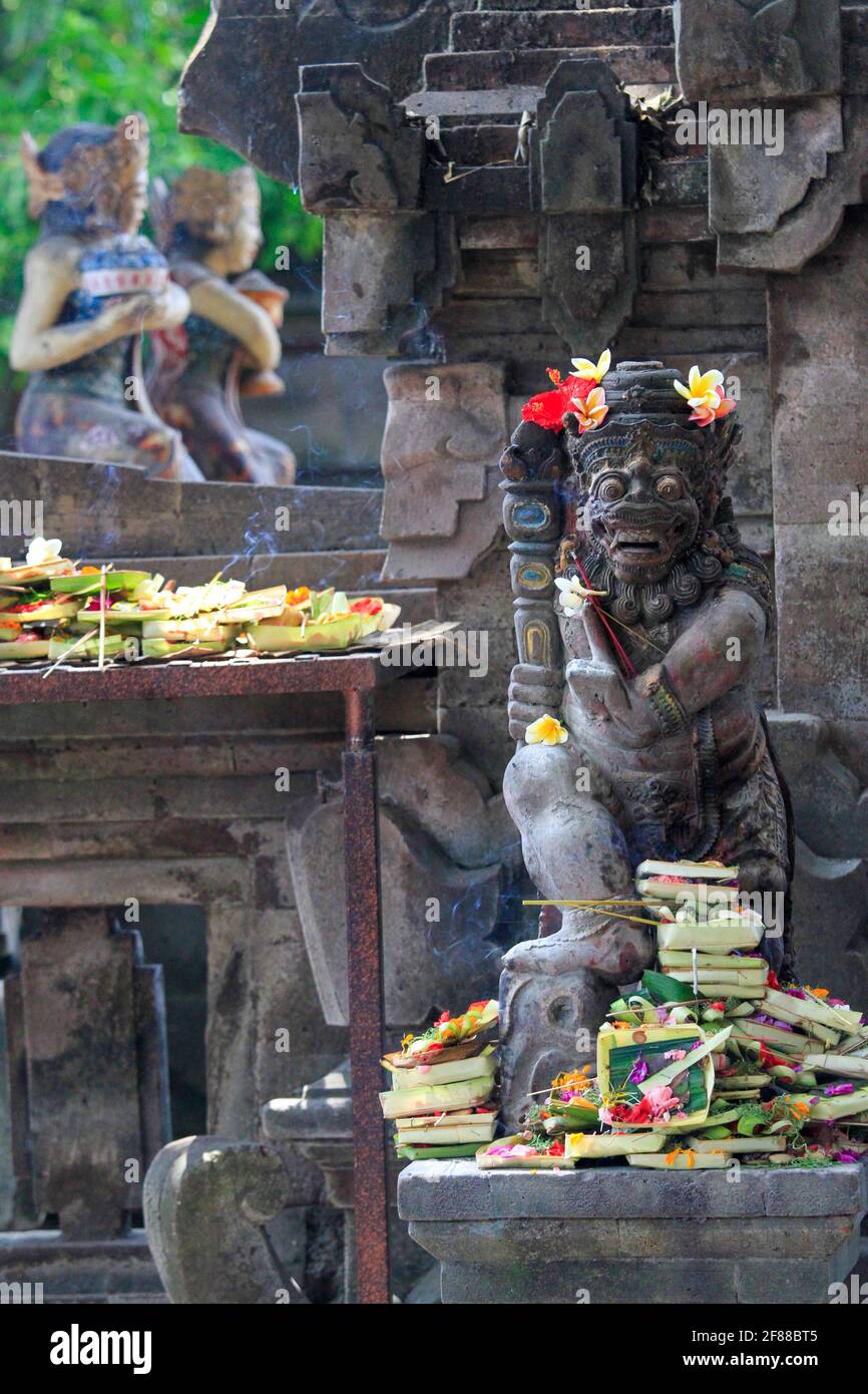 Traditional stone carved statue at temple with flower offerings and ...