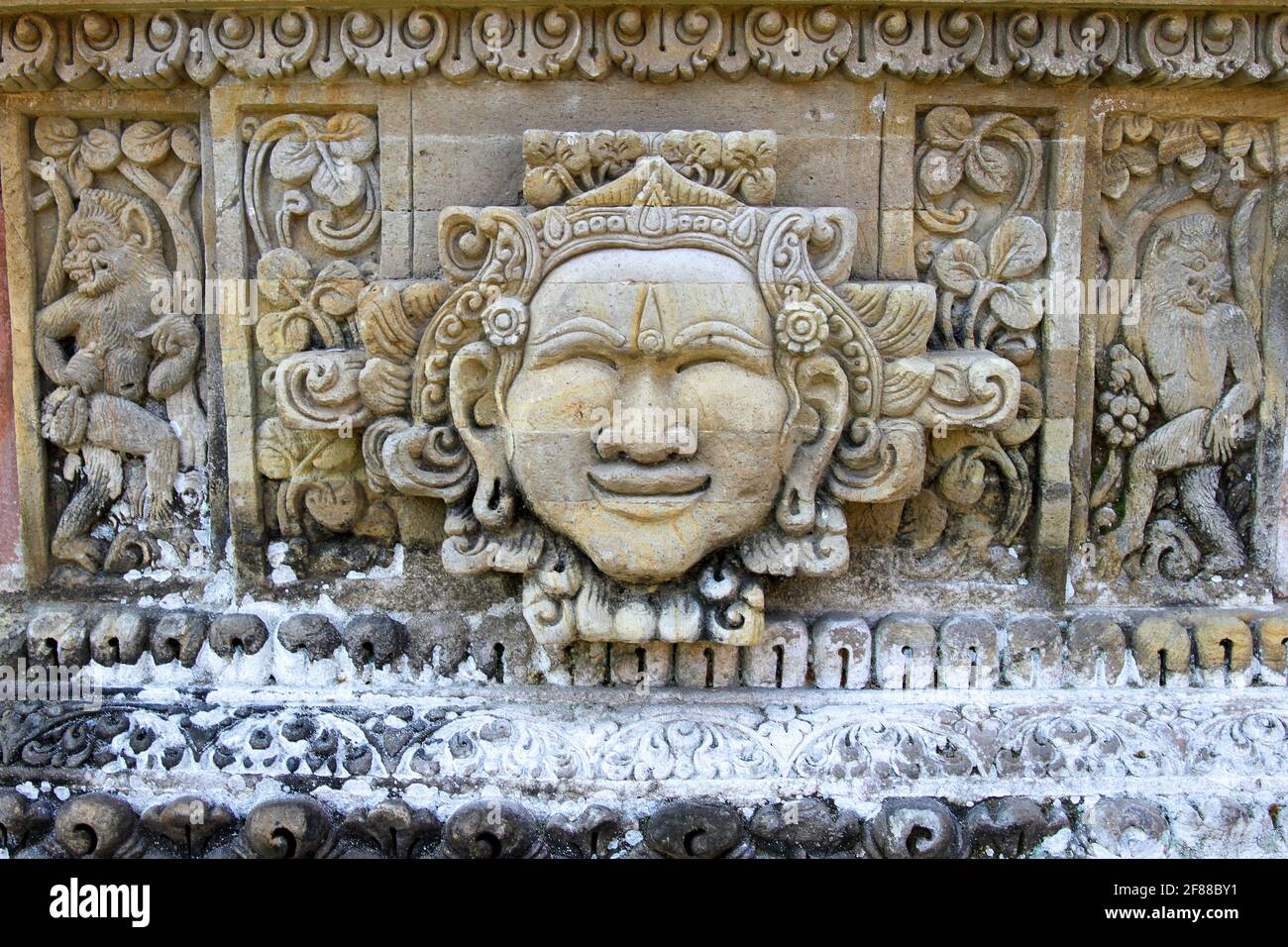 Traditional stone carving of face and monkeys in temple in Bali ...