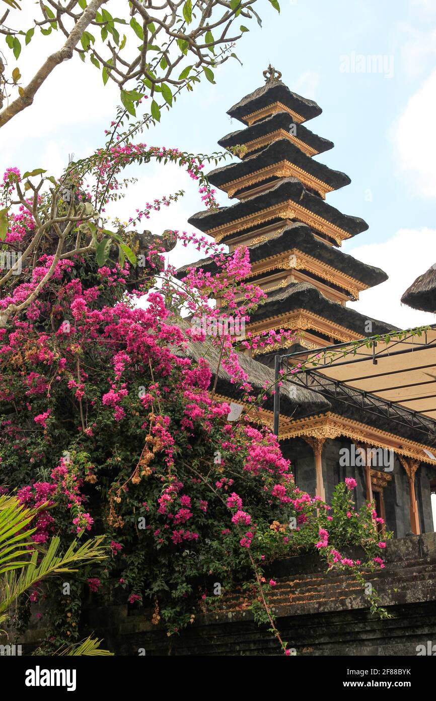 Tower of temple against blue sky framed by pink flowers in Bali ...