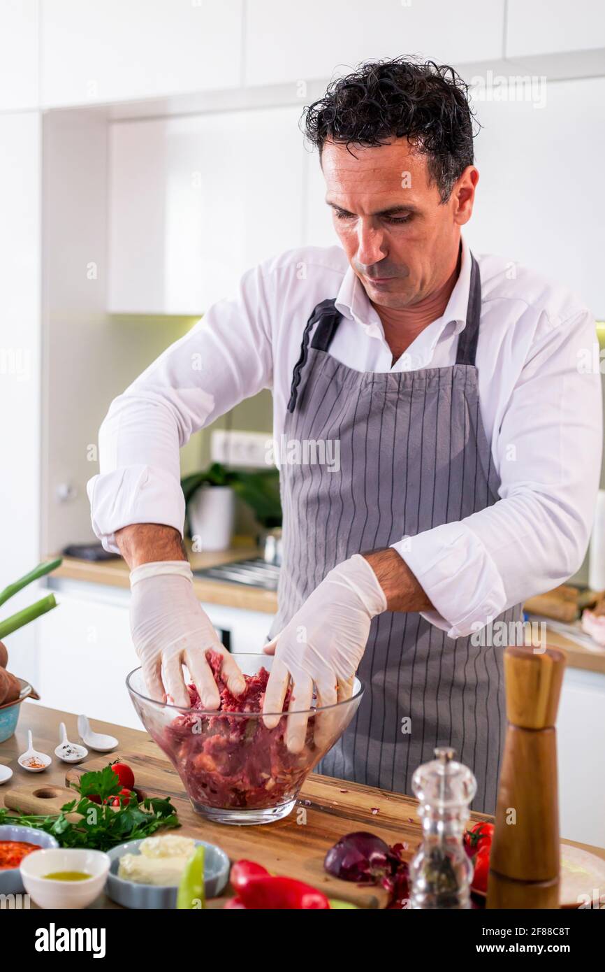 The chef mixing meatballs with spices and vegetables in a transparent ...