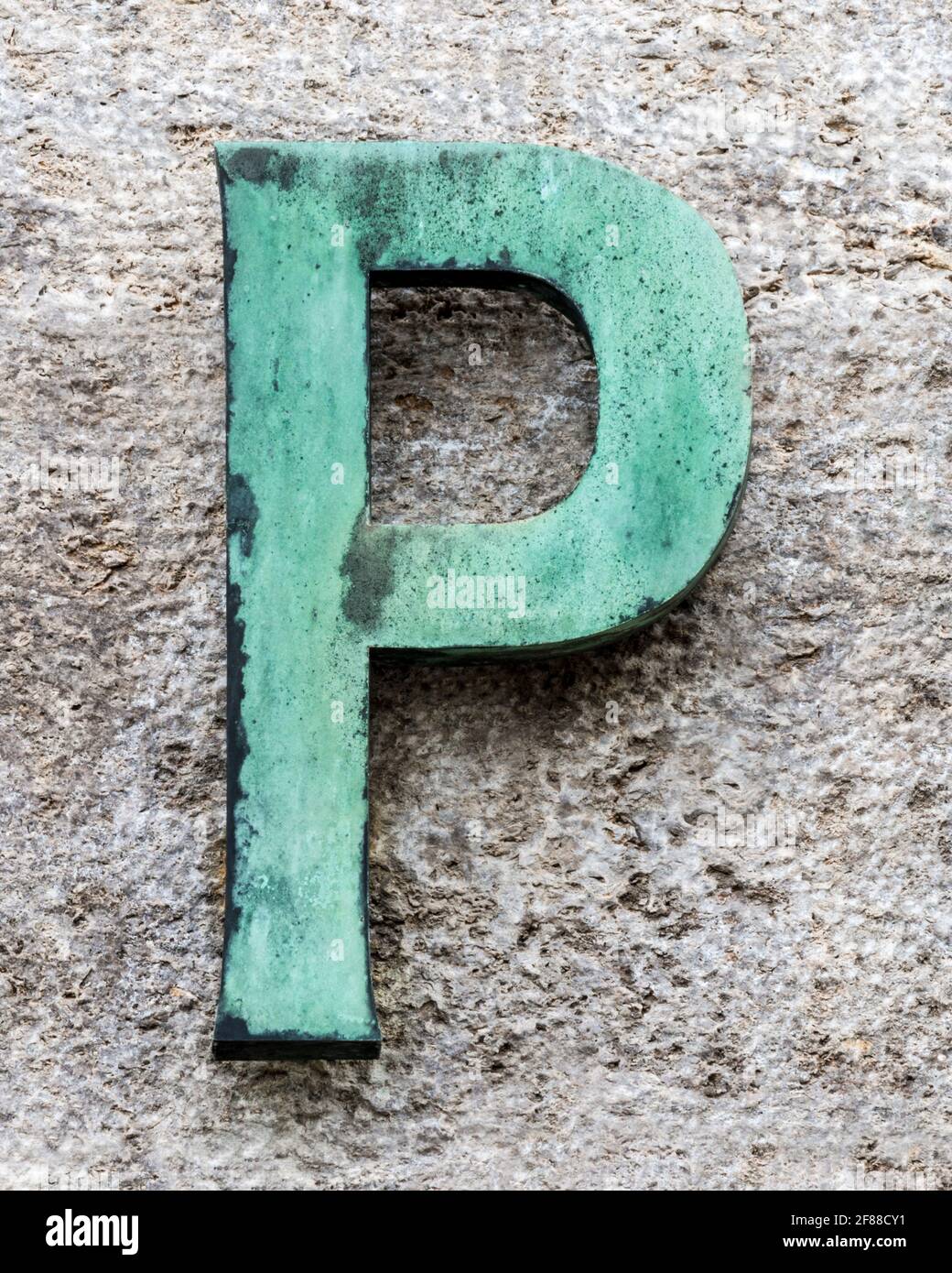 Metal letter P covered with verdigris on a natural stone wall Stock ...