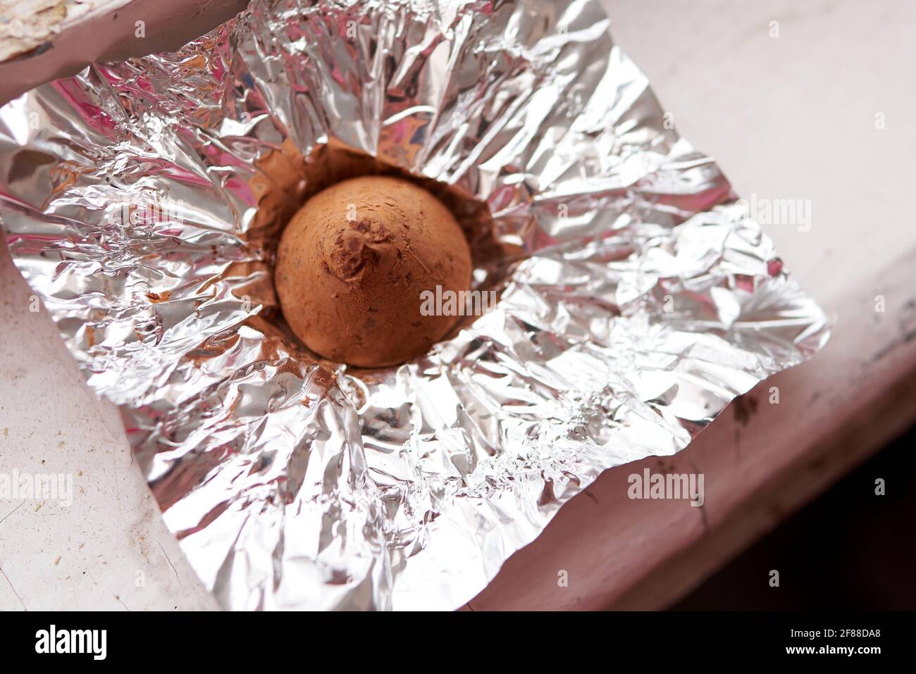 A chocolate truffle candy wrapped in a foil wrapper Stock Photo - Alamy
