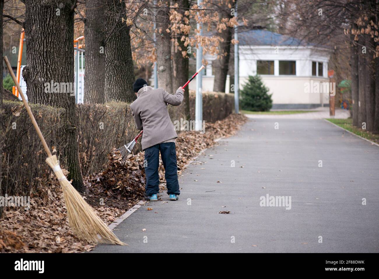 cleaning the park with a janitor and a broom Stock Photo - Alamy