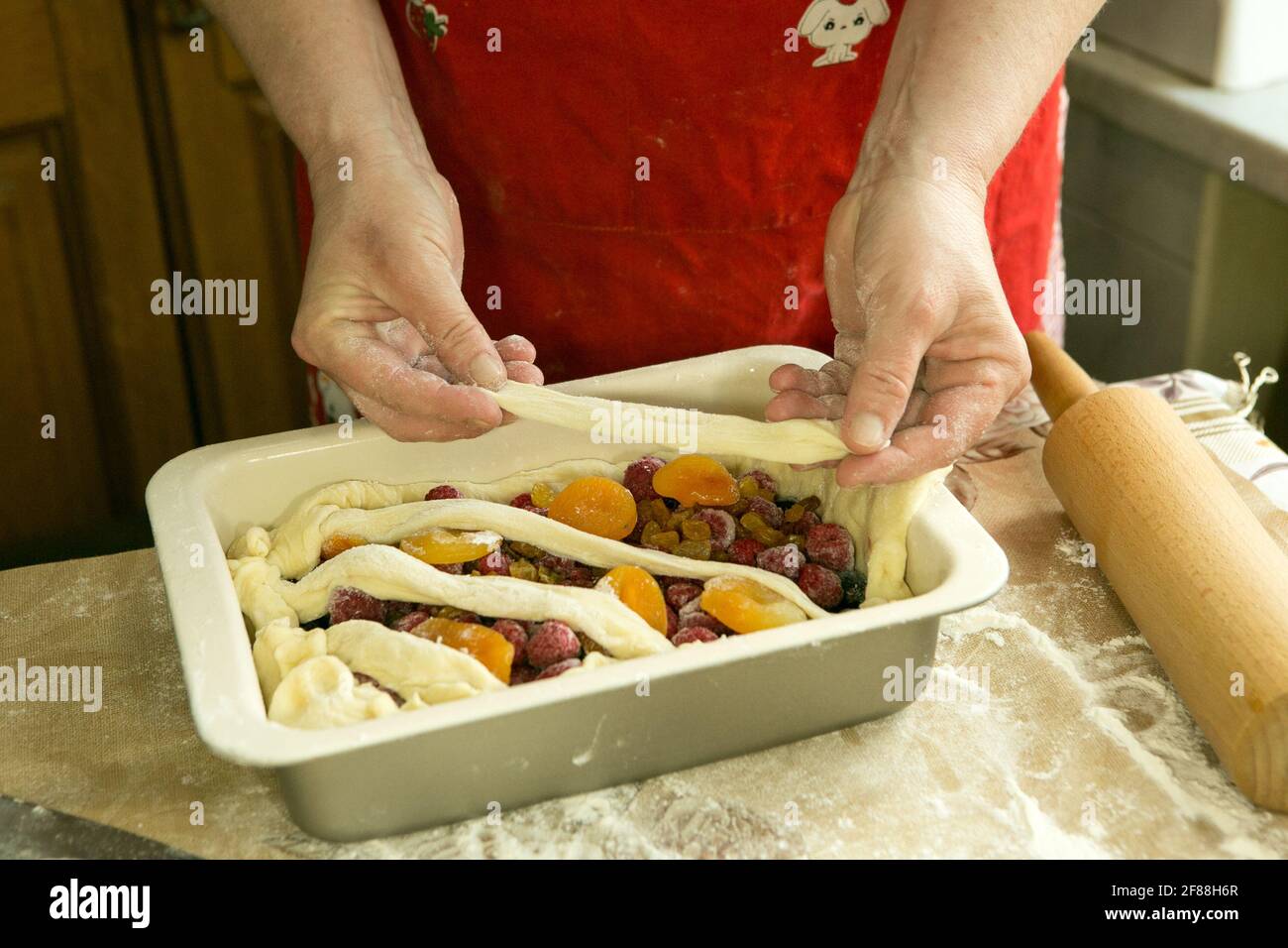 Mom's pies. Mom covers the pie with strips of dough. Female hands ...