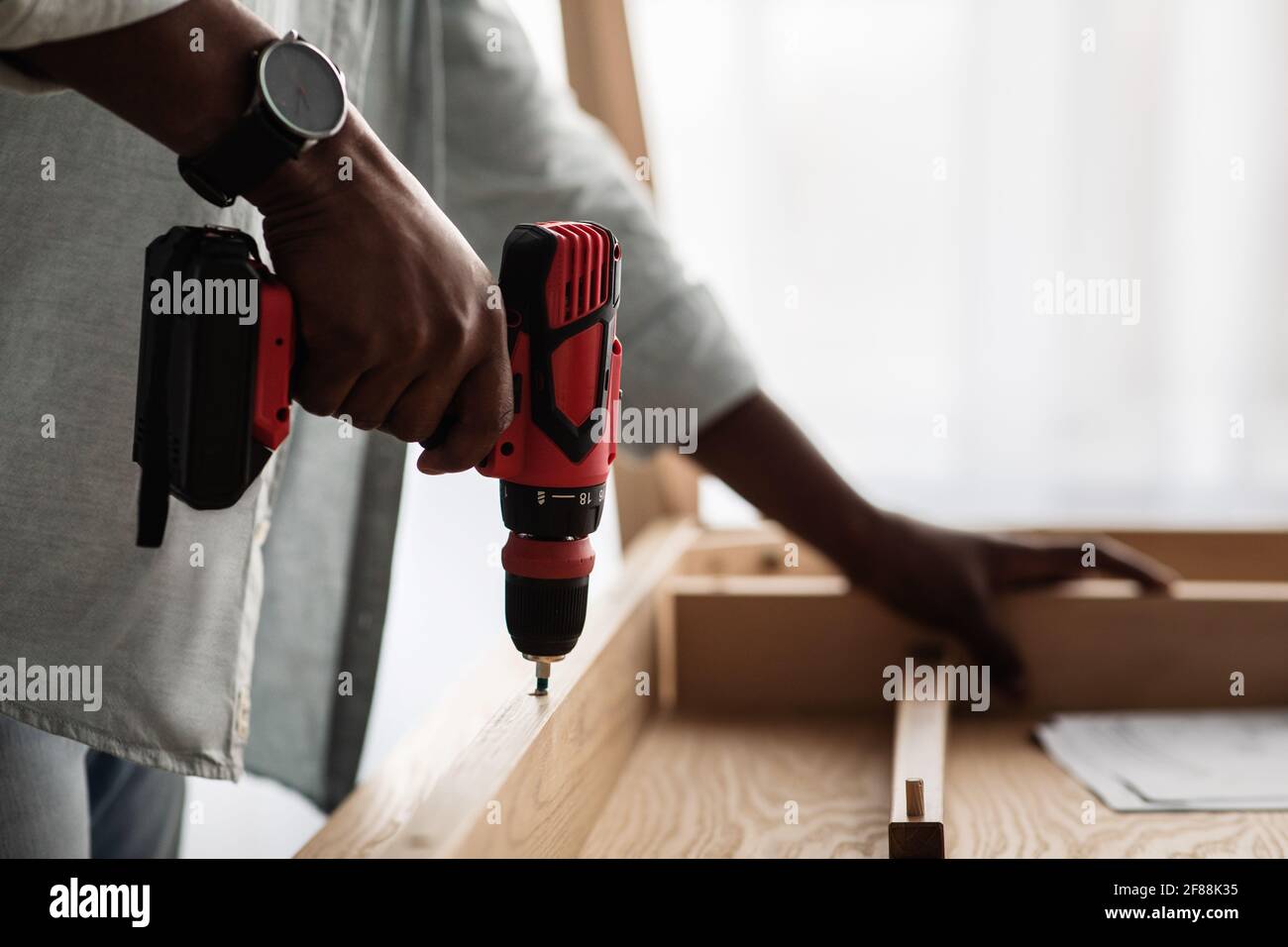Unrecognizable Black Man Assembling Table Screwing Details Of Desk