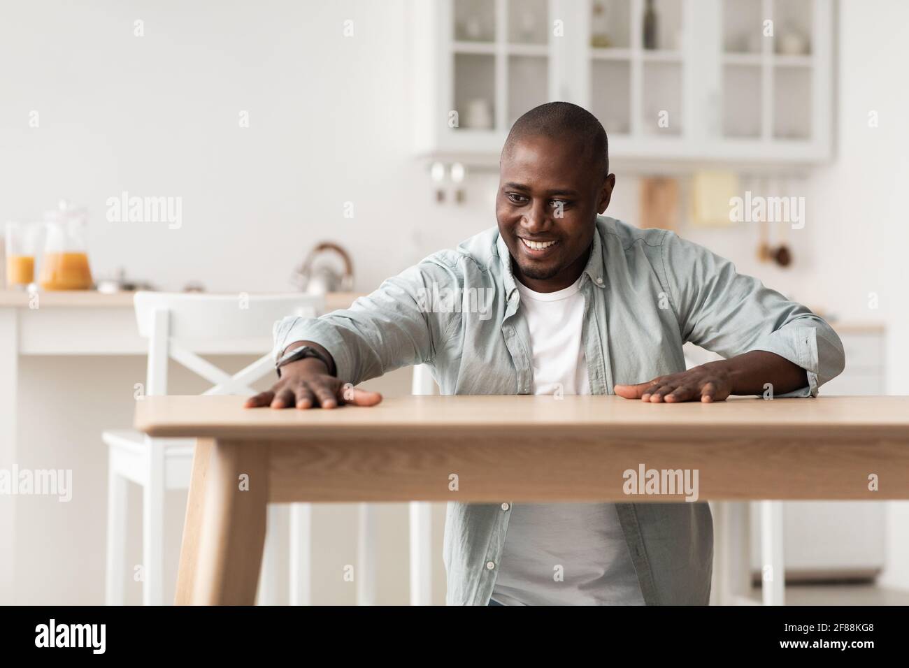 Happy african american man touching new wooden table, feeling pleasure ...