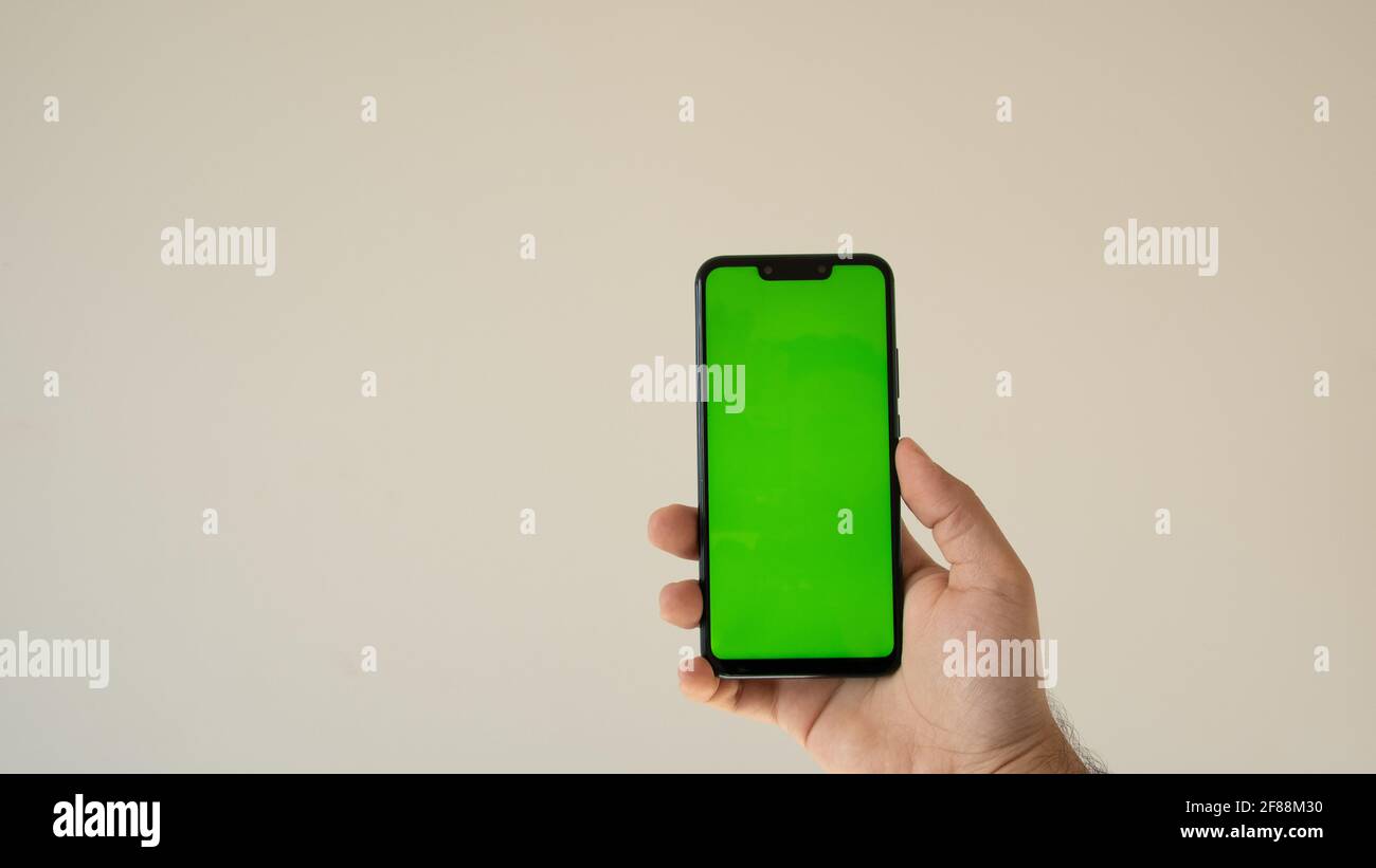 human holding mobile phone with notched and green screen in hand Stock ...