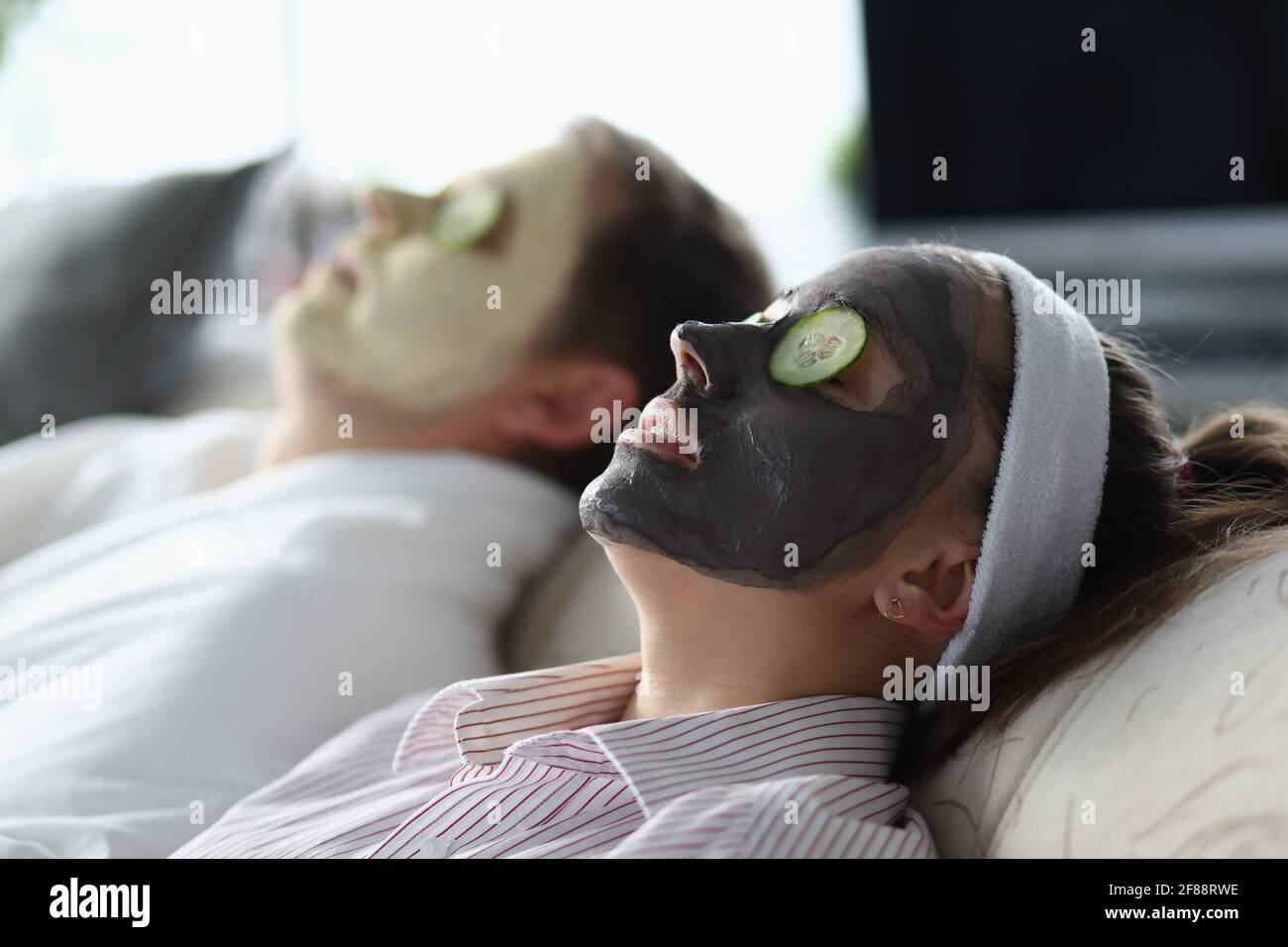 Young man and woman lying with cosmetic masks on their faces and ...