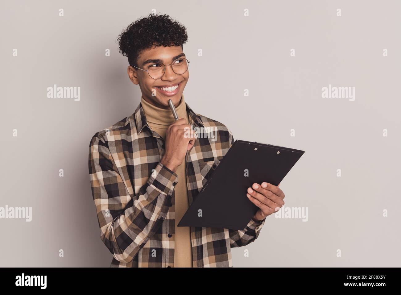 Photo portrait of dreamy curious guy writing exam on clipboard ...