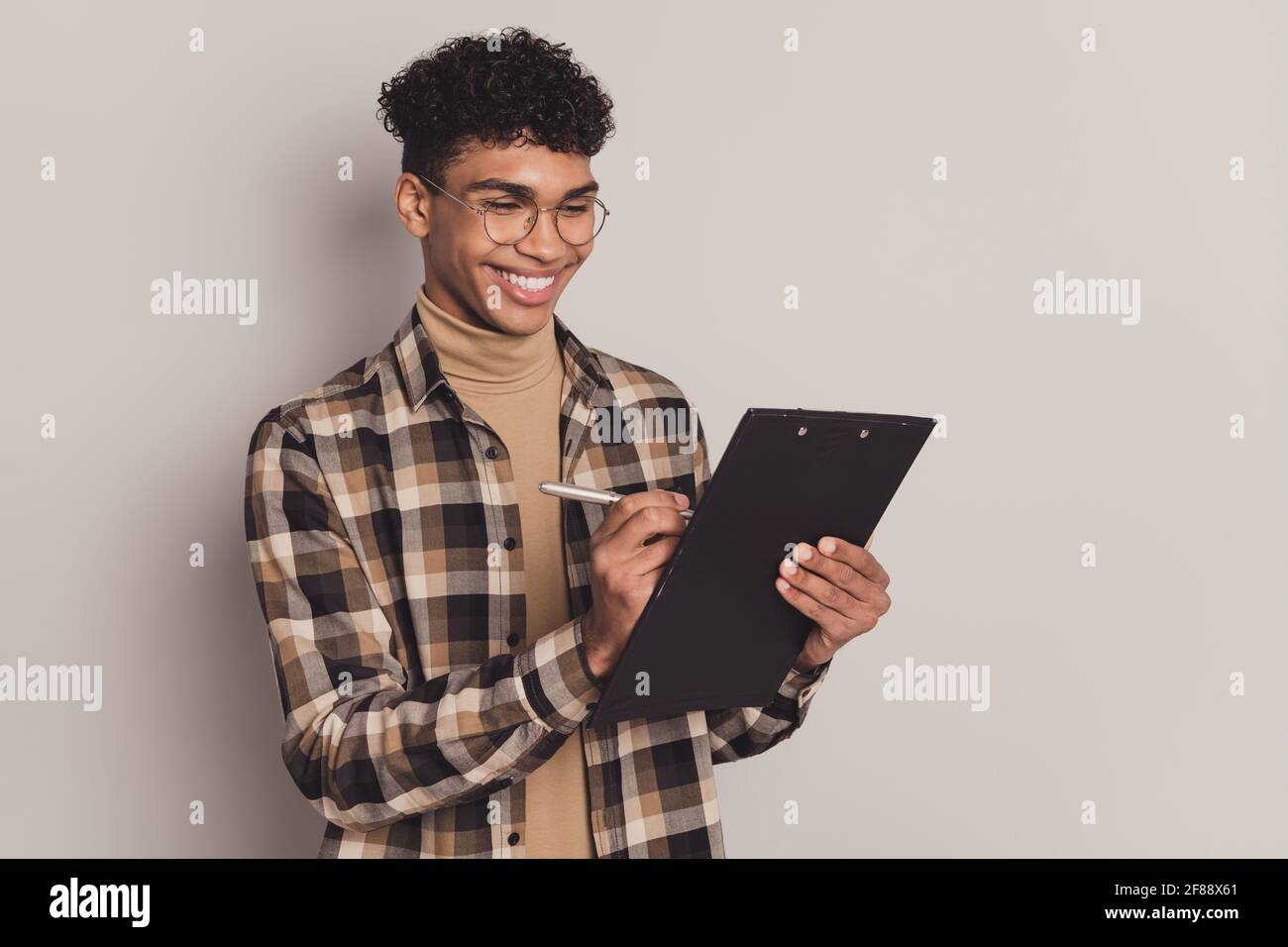 Photo portrait of guy writing test exam on clipboard interview smiling ...