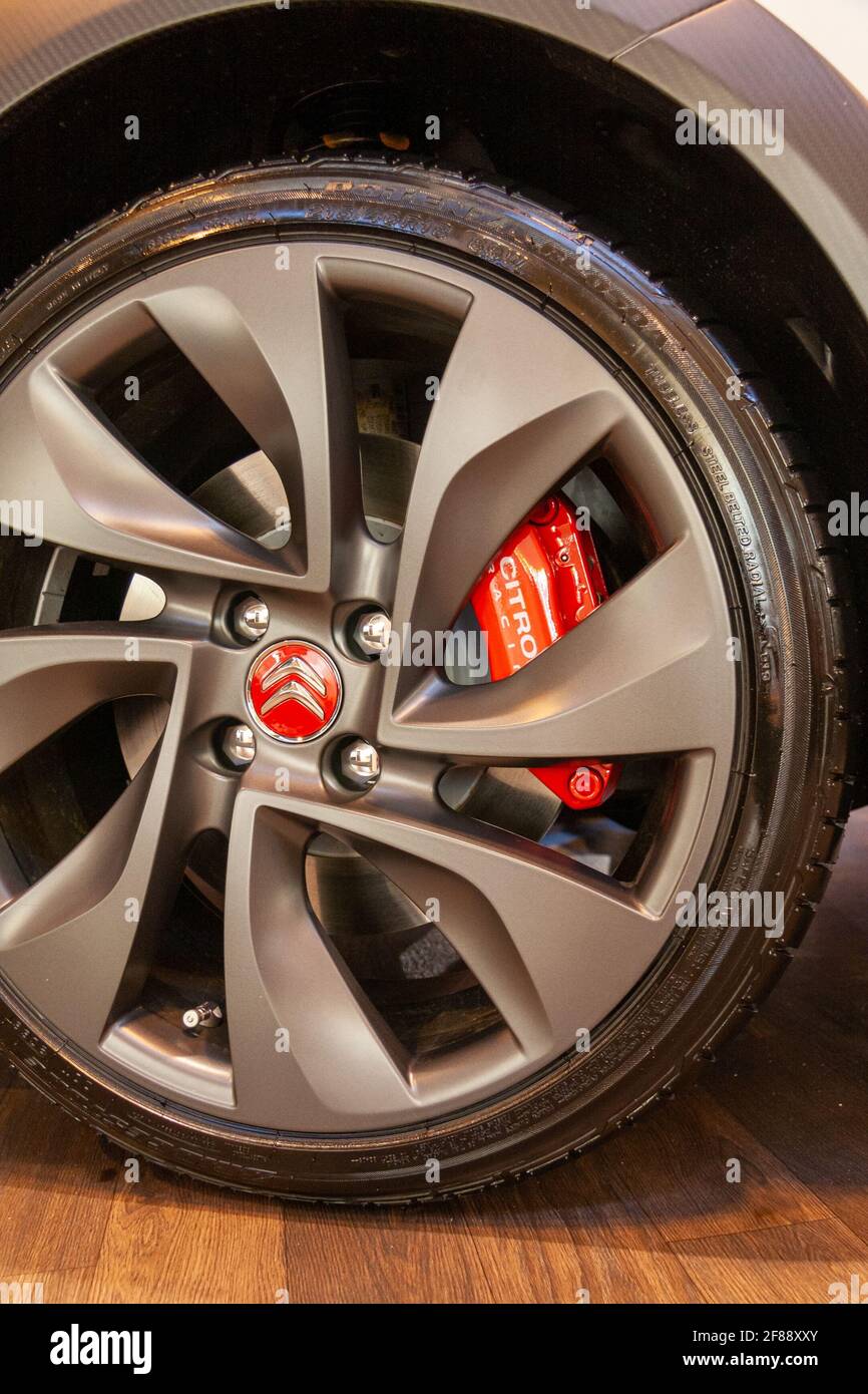 The metallic grey alloy wheel of a Citroen car with a bright red ...