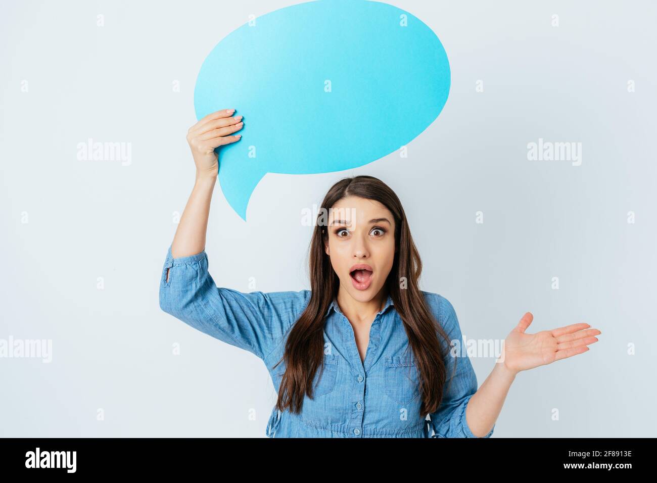 Surprised excited young woman holding chat bubble above her head with ...