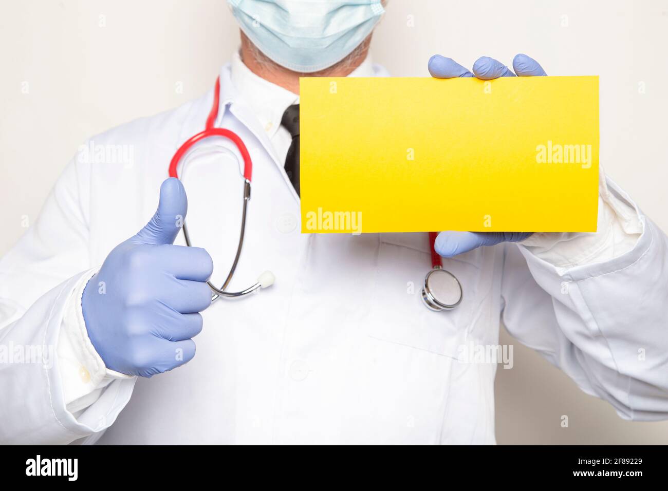 Close up of a male doctor making a positive gesture holding a sign with ...