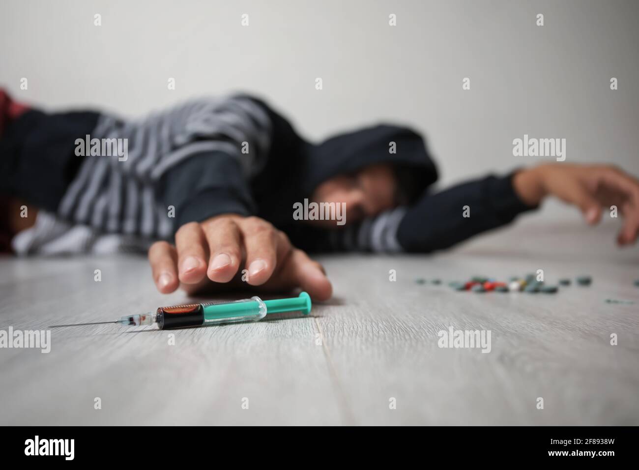 Male junkie with syringe lying on floor Stock Photo - Alamy