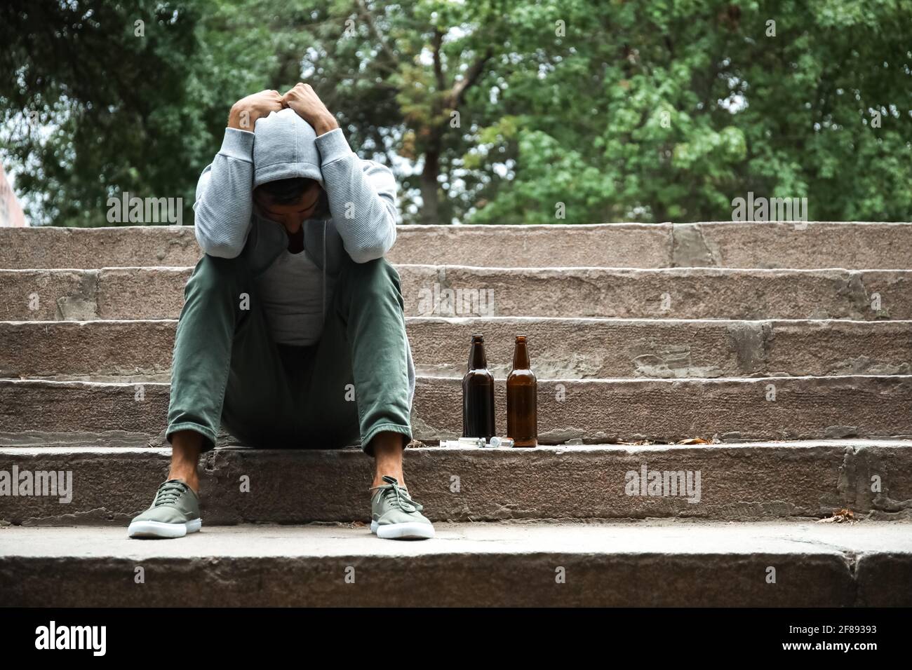 Male junkie with drugs and alcohol sitting on stairs outdoors Stock ...
