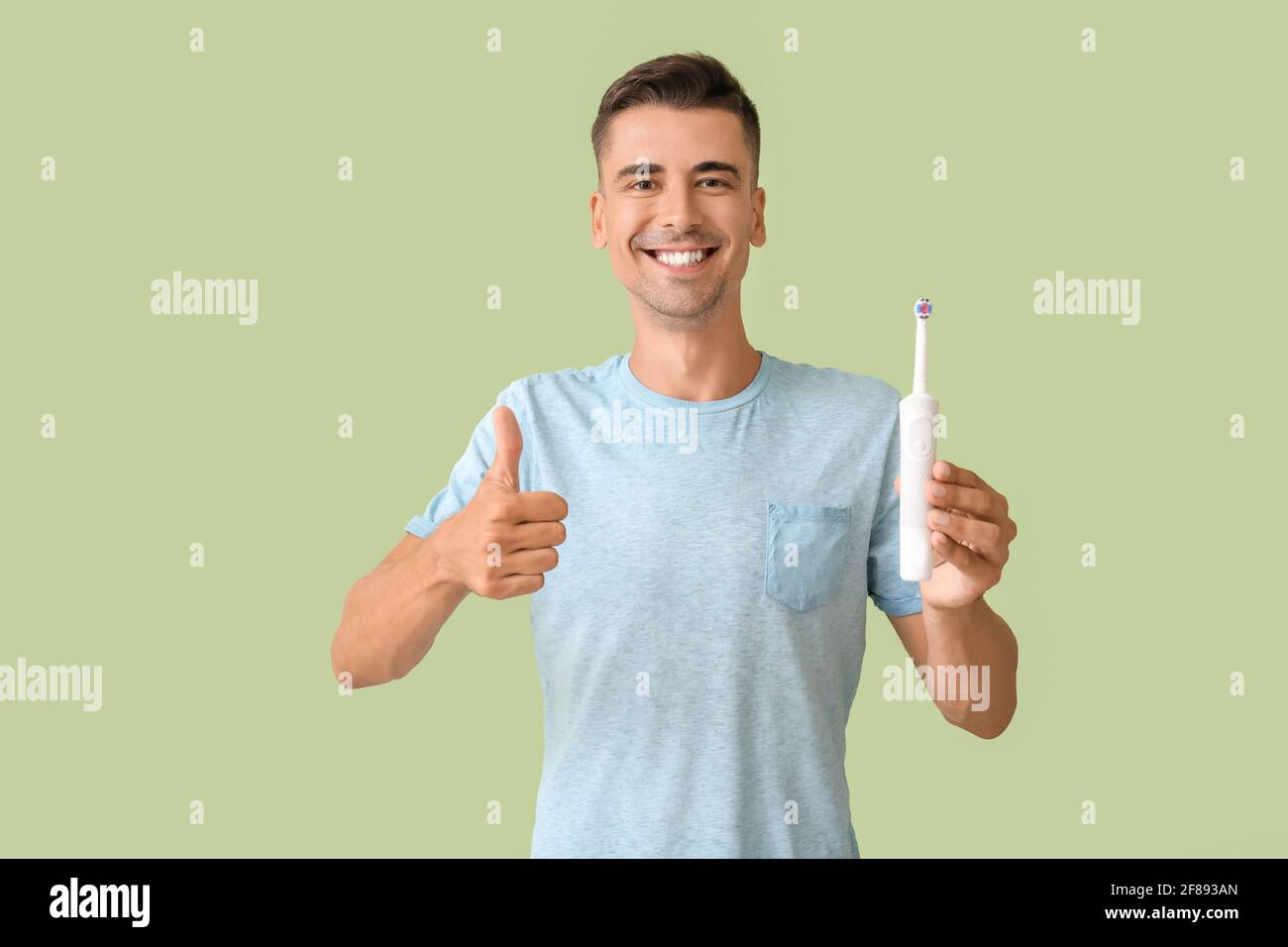 Young man with toothbrush showing thumb-up on color background Stock ...
