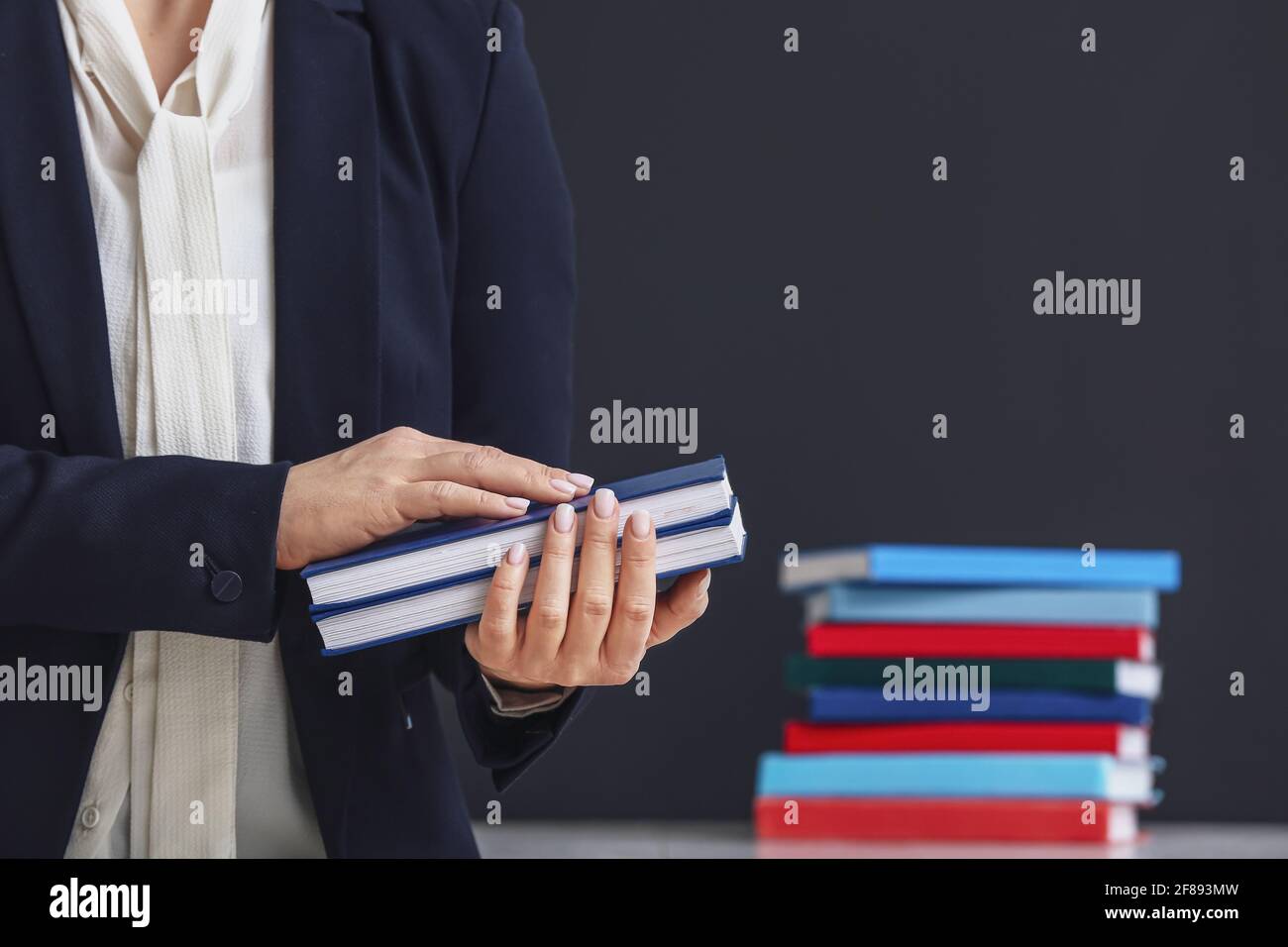 Female teacher with books in classroom, closeup Stock Photo - Alamy