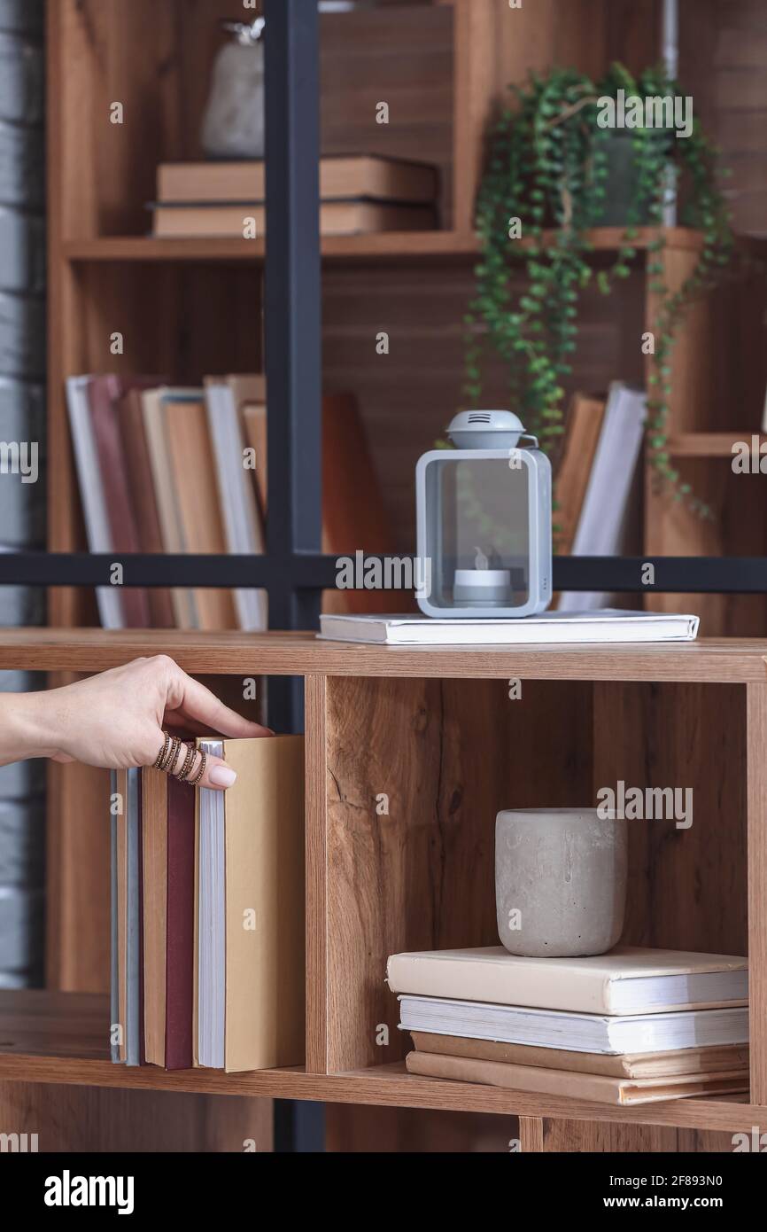 Woman taking book from shelf Stock Photo - Alamy