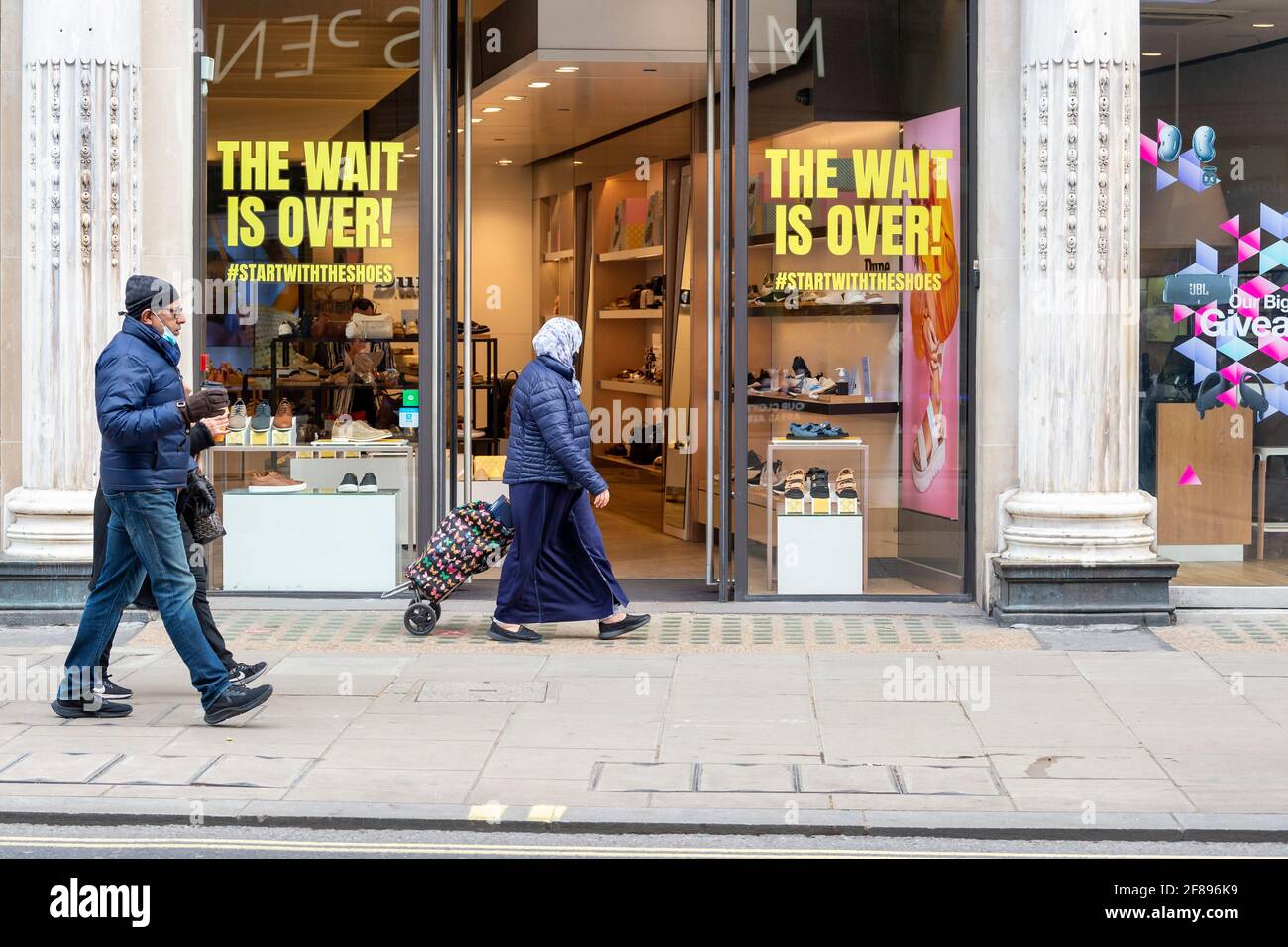Shoppers in Oxford Street walk past a window sign saying ‘the wait is ...