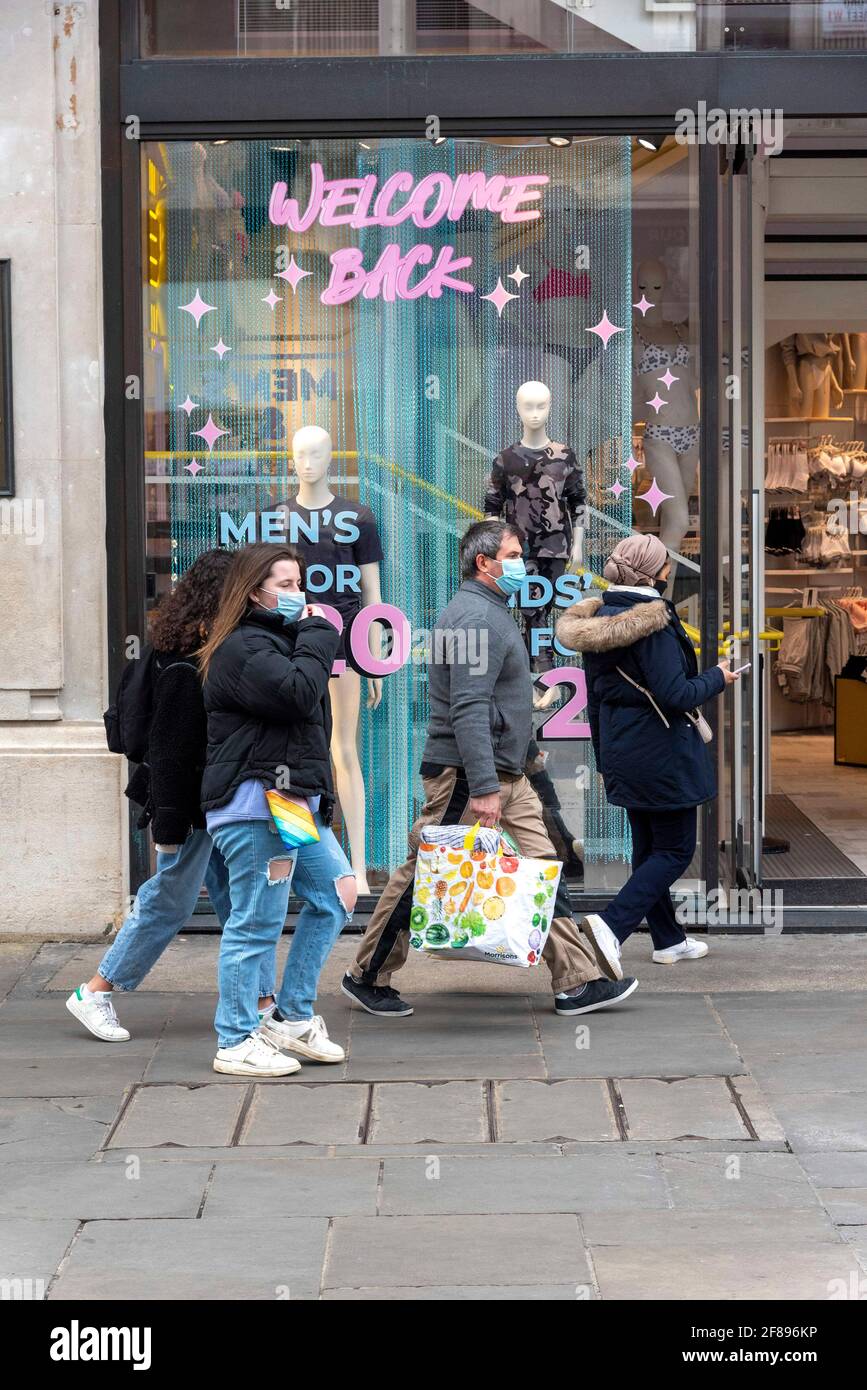 Shoppers in Oxford Street seen walking past a window with a sign behind ...