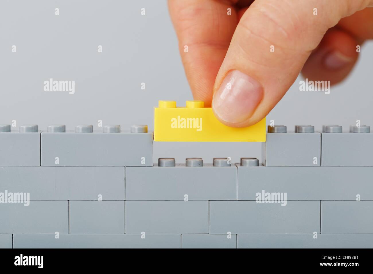 The hand puts the last yellow brick on the gray wall from the ...
