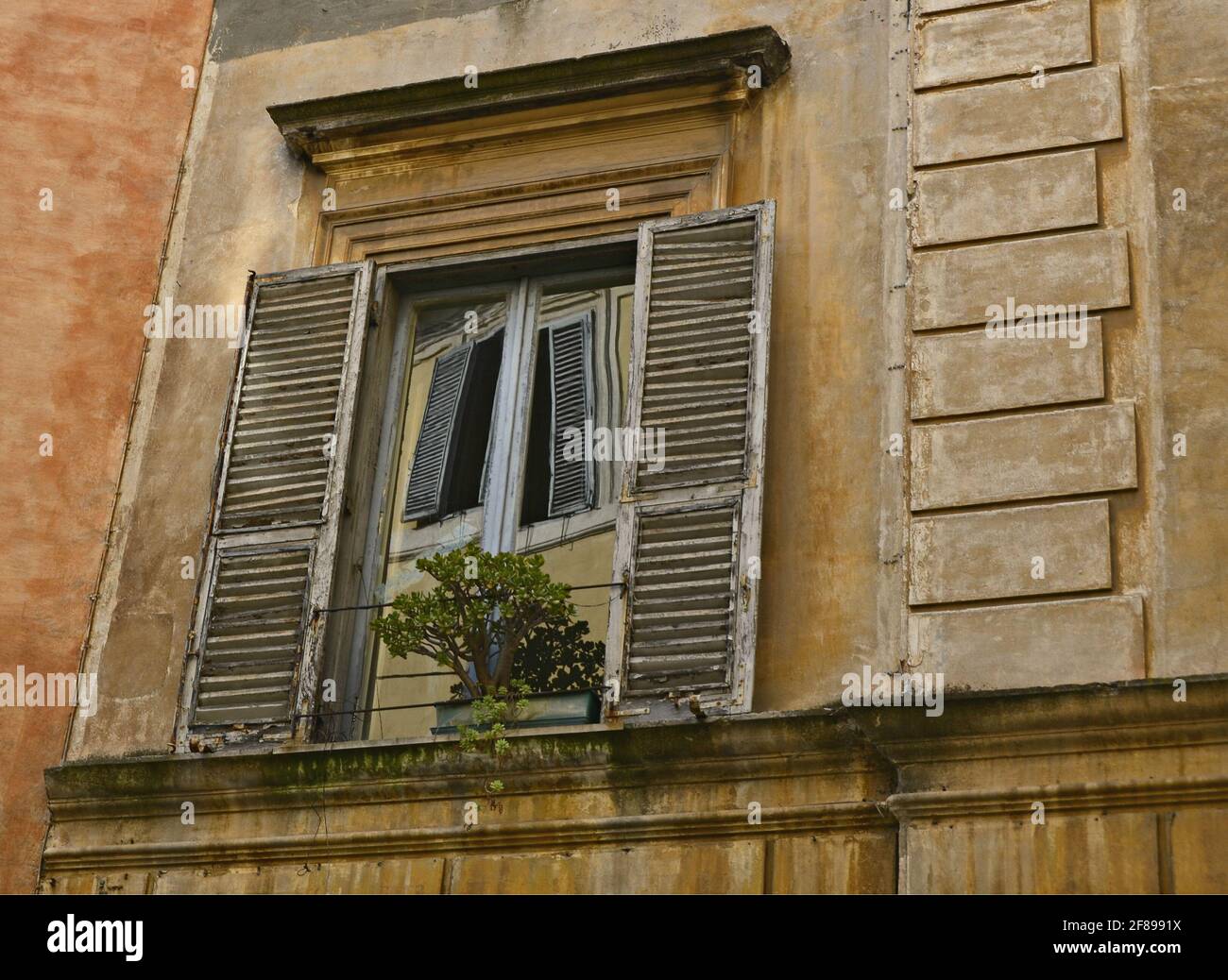 Neoclassical building window with weathered wooden window shutters on a ...
