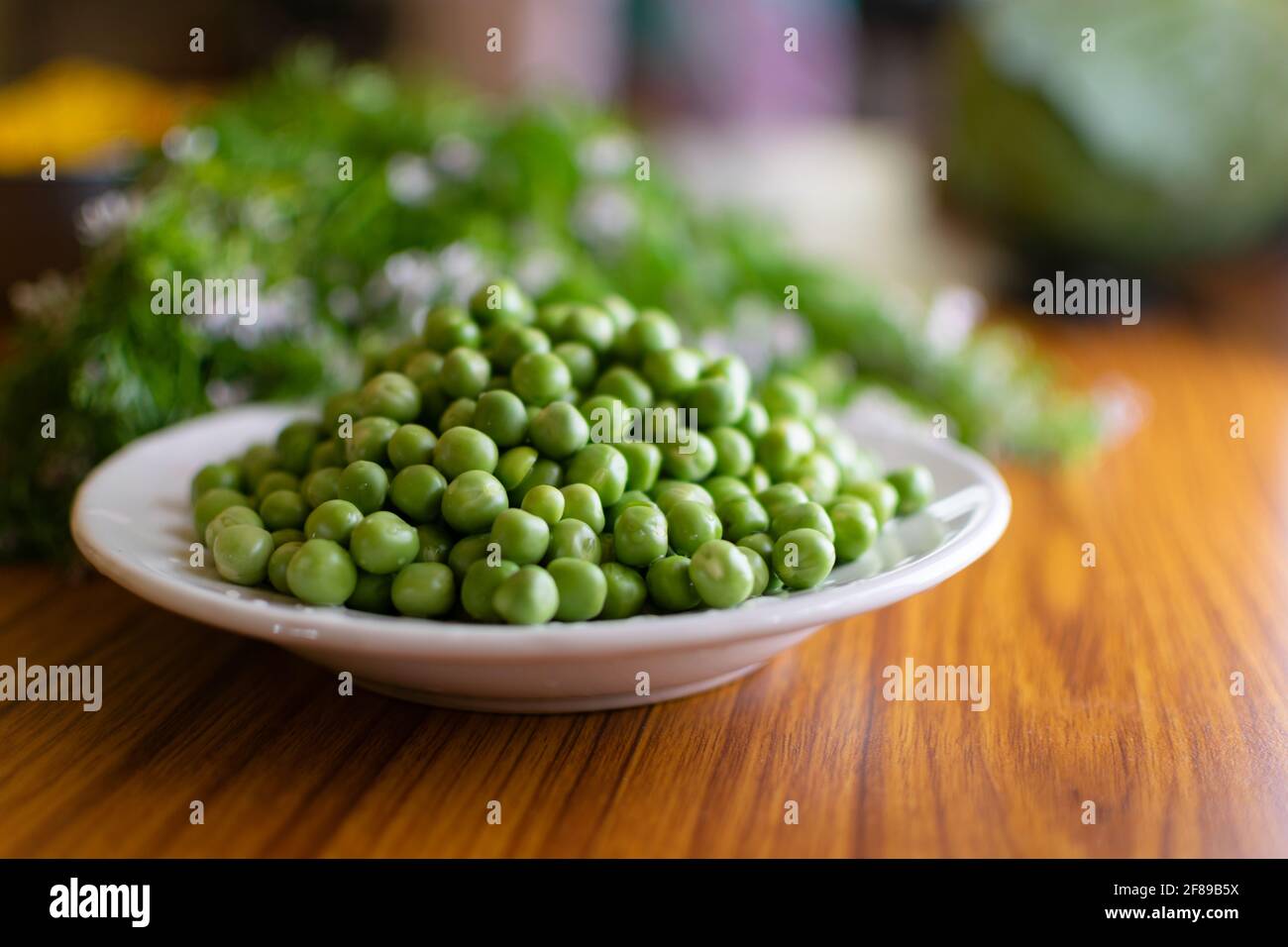 Green peas vegetable uncooked in the white plate with selective focus ...