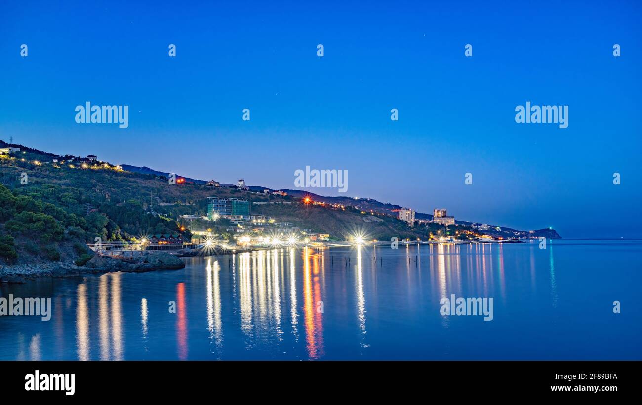 Green sea shore with residential buildings in the night. Seascape with ...