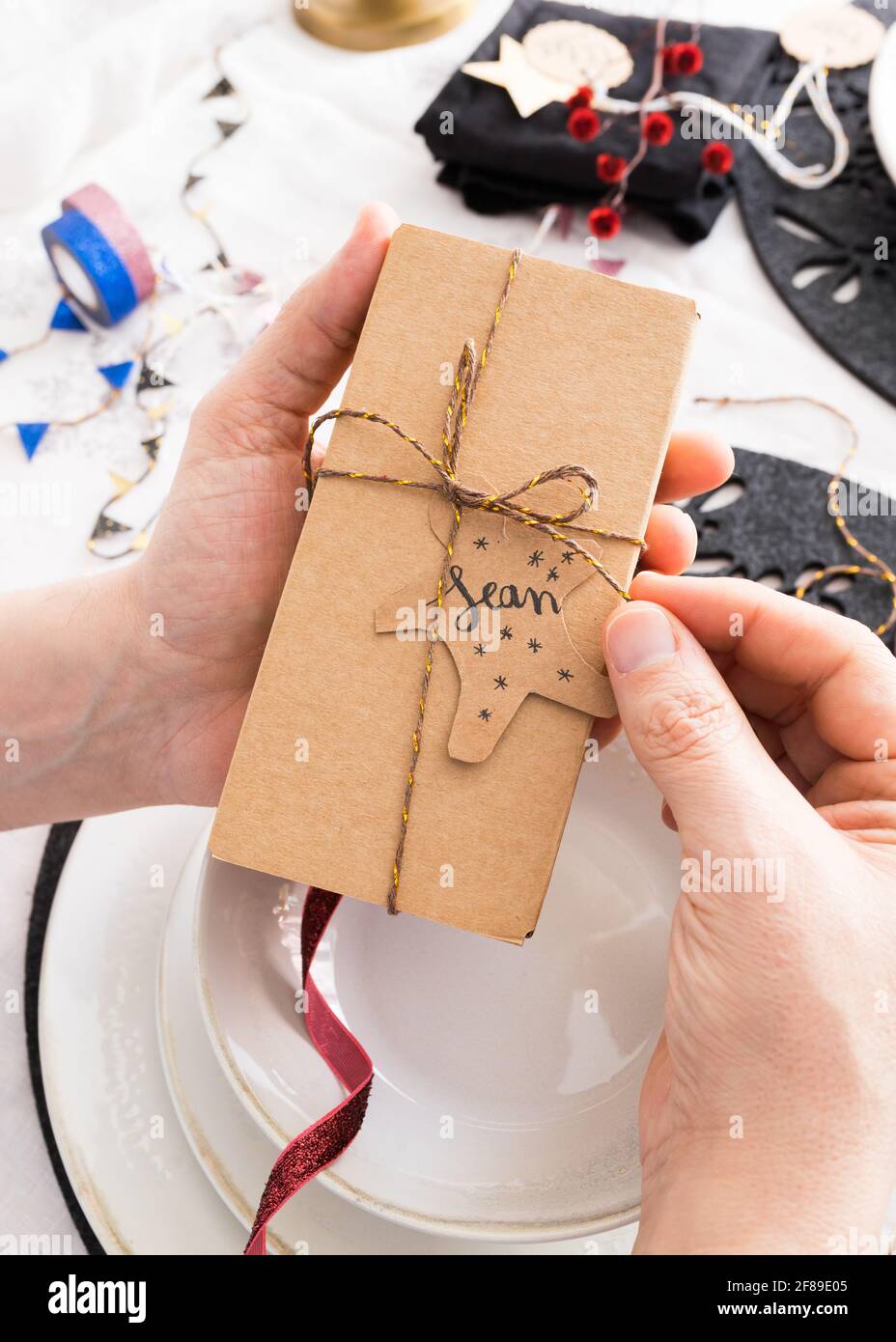 Christmas gift box tied with golden ribbon forming a bow being opened ...