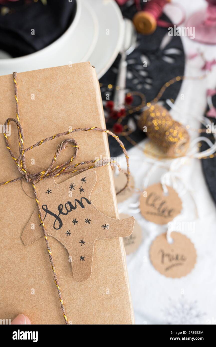 Closeup view of a Christmas gift box tied with golden ribbon . The name ...