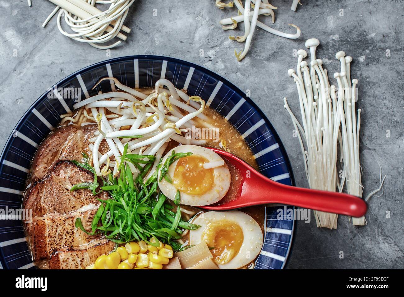 Asian noodle ramen with pork, marinated egg, sprout on grey clay ...