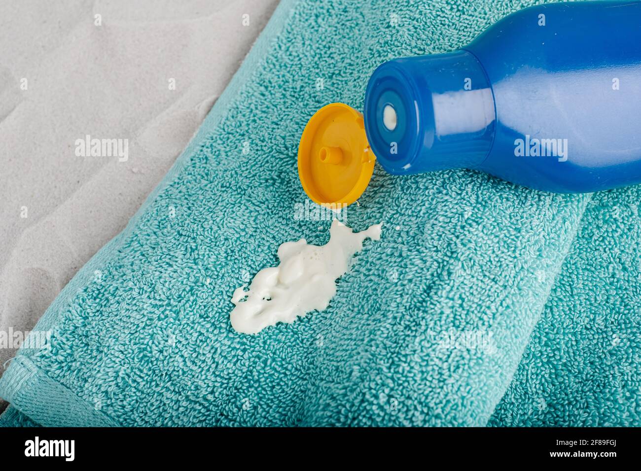 Sunscreen lotion spilling on a turquoise towel. Daily life dirty stain ...