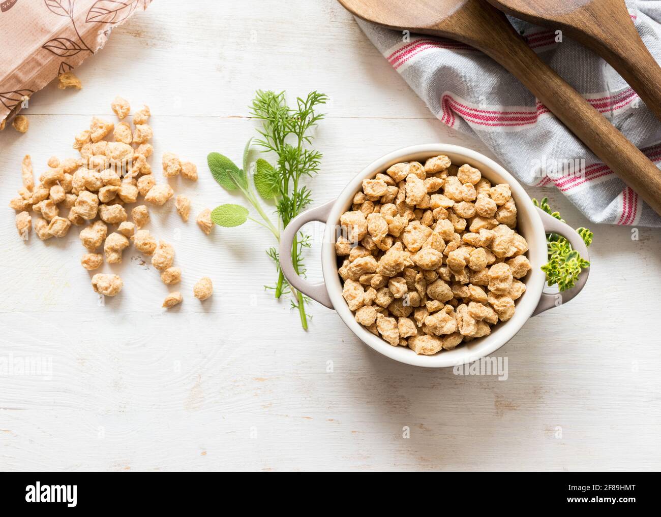 A white casserole full of raw chunks of soya. Some pieces of soya meat ...