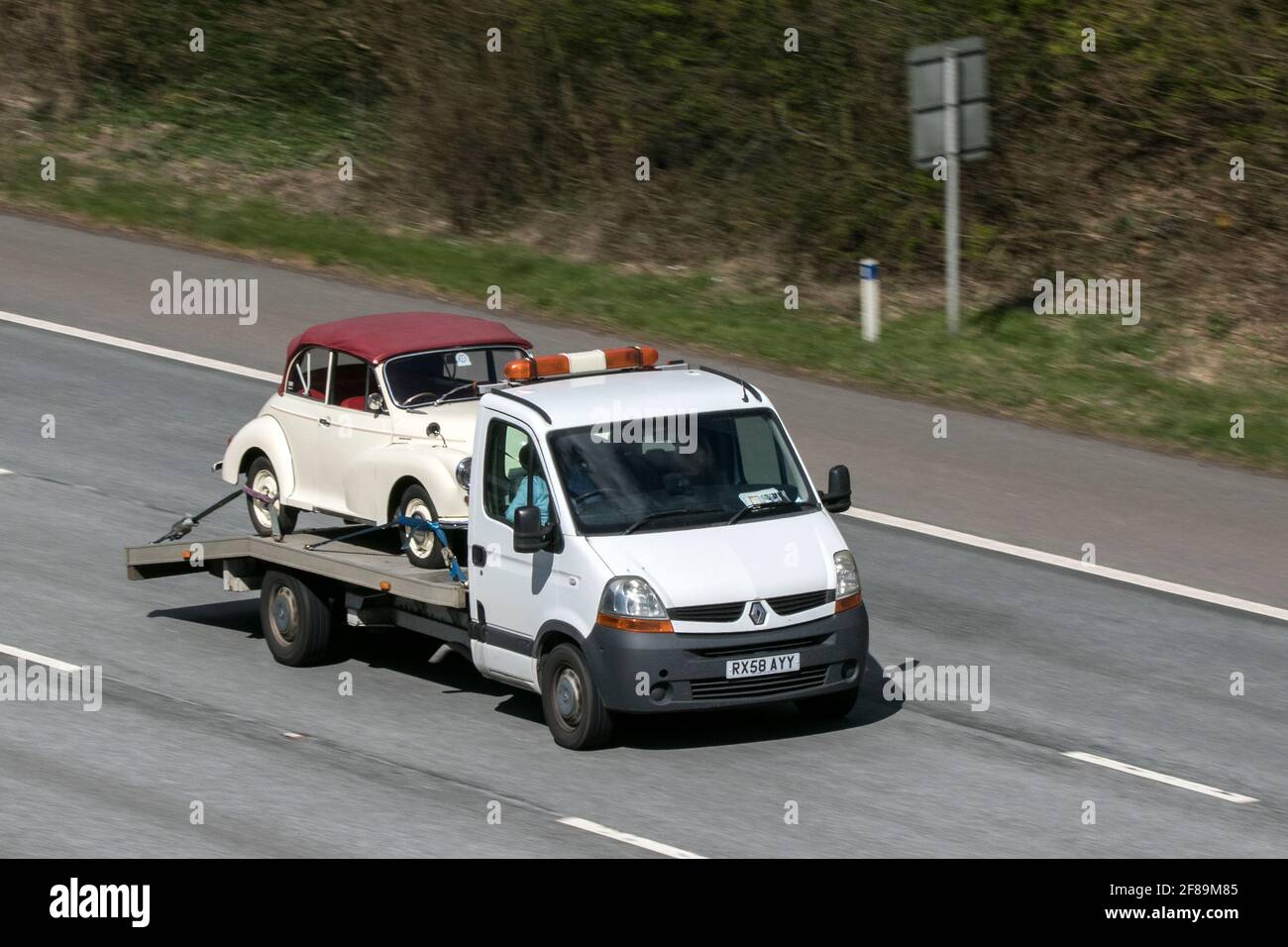 Classic Morris Minor convertible car on low-loader driving on the M6 ...