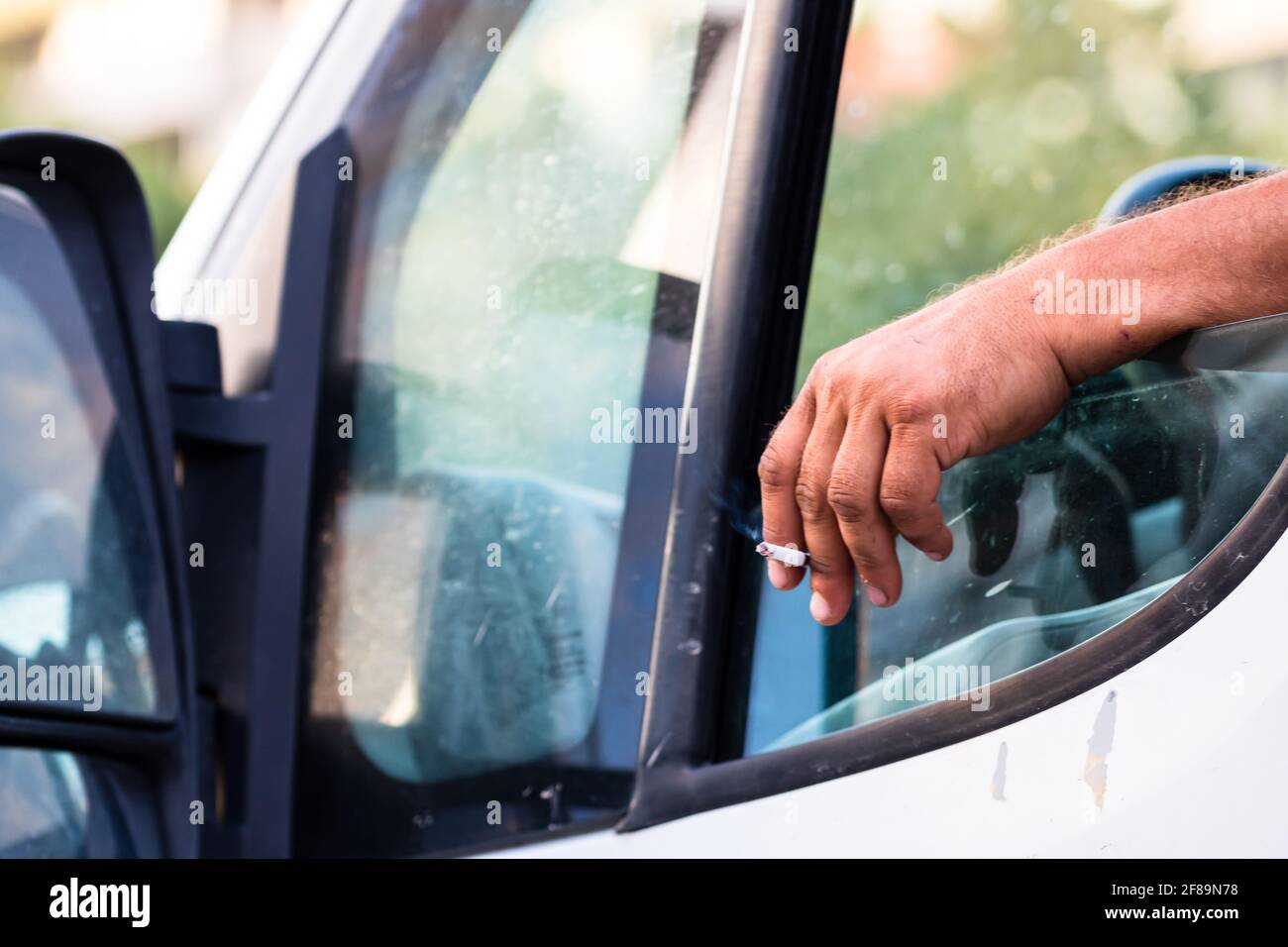 Driver holding hand on car door with open window, waiting in traffic ...