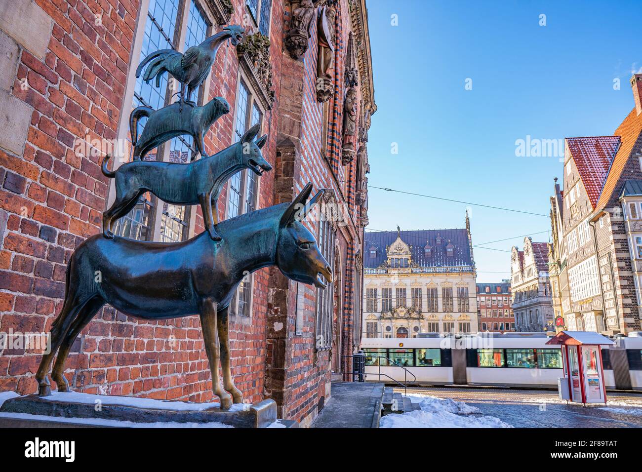 side view of Town Musicians of Bremen statue in winter with train in ...