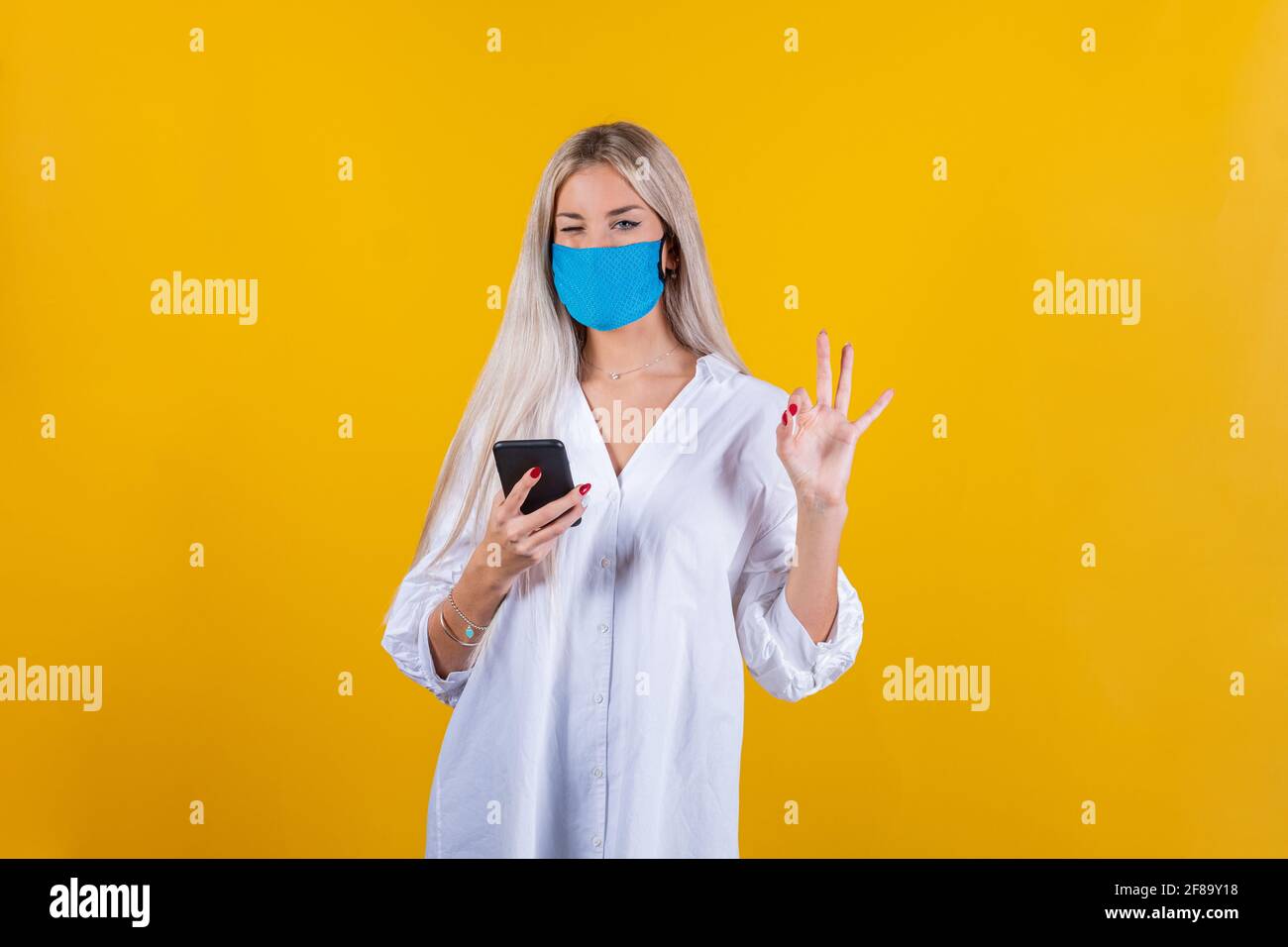 Woman wearing face mask protect from virus showing ok sign. Young girl ...