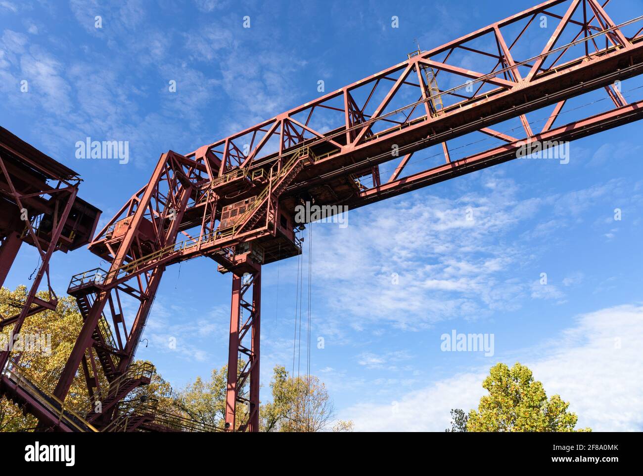 Massive overhead steel structure silhouetted against a bright blue sky ...