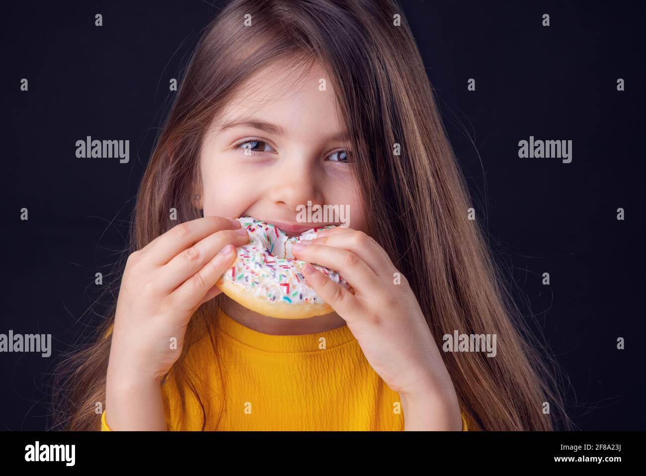 Sweet little girl eating white donut Stock Photo - Alamy