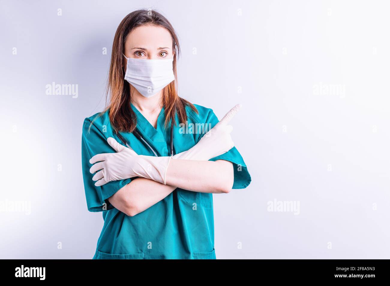 Surgeon doctor pointing to a side with arms crossed looking straight ...